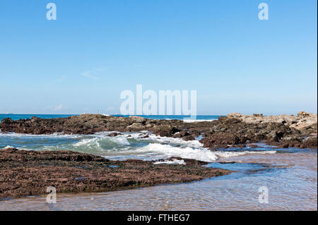 The sea waves splash over the rocks near the shore, in front of high ...
