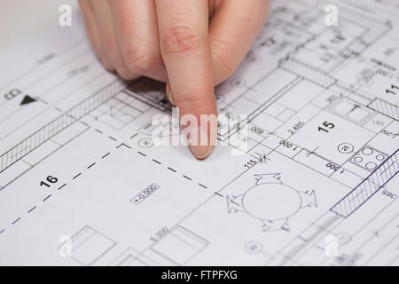 Finger from an unknown person is showing at the plan of the house. Blue ...