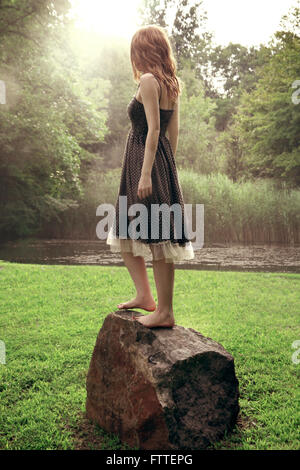 Woman looking away while standing on grassy field during sunny day ...
