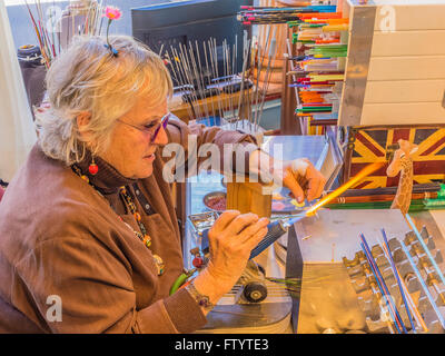 Kate Drew-Wilkinson glass artist sits at her work bench in her glass ...