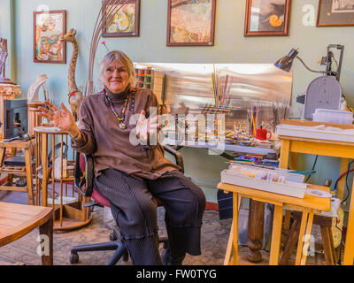 Kate Drew-Wilkinson glass artist sits at her work bench in her glass ...