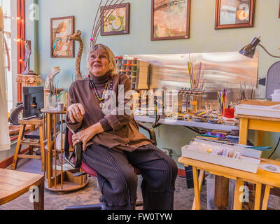 Kate Drew-Wilkinson glass artist sits at her work bench in her glass ...
