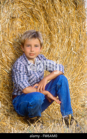 Portrait of a boy sitting against a hay bale Stock Photo - Alamy