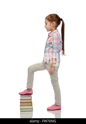 happy little girl stepping on book pile Stock Photo - Alamy