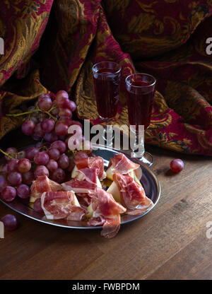 Spanish jamon with melon and grape on a wooden table Stock Photo - Alamy
