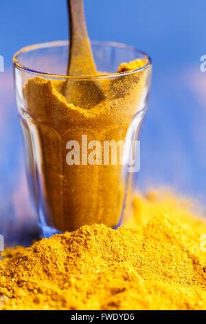 Turmeric powder in a wooden spoon and roots on a dark table (curcuma ...