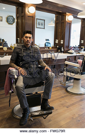 Man sitting in barber shop during barber have cut his hair. Back view ...