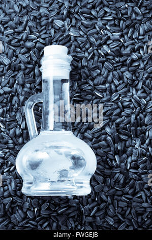 Jug of oil, sunflower and jar with seeds on brown background Stock ...