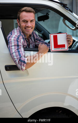 Man holding a learner driver sign sitting behind the wheel Stock Photo ...