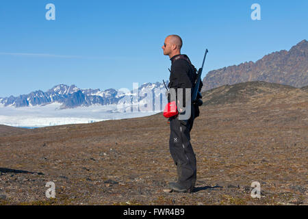 Polar bear guard armed with rifle looking for polar bears through ...