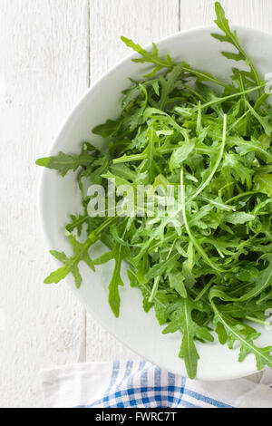 Fresh green arugula in a rustic clay bowl on a wooden table. Healthy ...