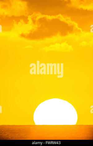 Sunset bright orange ball sinking Stock Photo - Alamy