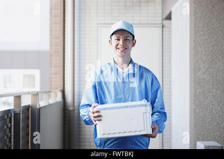 Japanese delivery man holding a box in his hand Stock Photo - Alamy