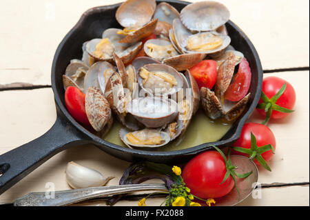 fresh clams stewed on an iron skillet over wite rustic wood table Stock ...