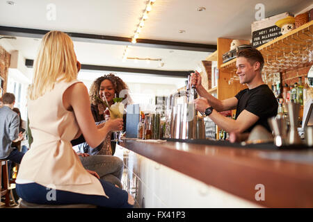 Bartender Serving Female Customers In Cocktail Bar Stock Photo - Alamy