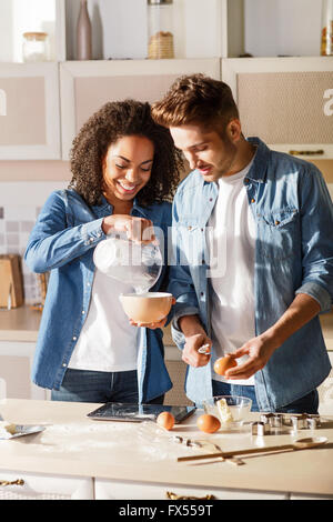 Young cook. Cheerful positive delighted girl sitting in the kitchen and ...