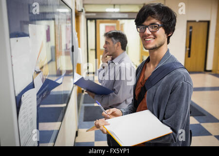 Male student reading notice board in college Stock Photo - Alamy