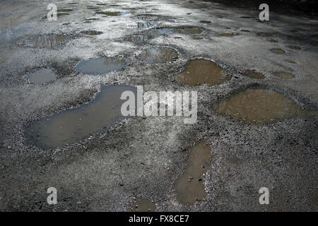 puddles formed in the surface indentations of a tarmacked car park ...