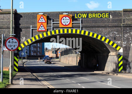 Brick railway bridge with height restriction sign across a road in ...