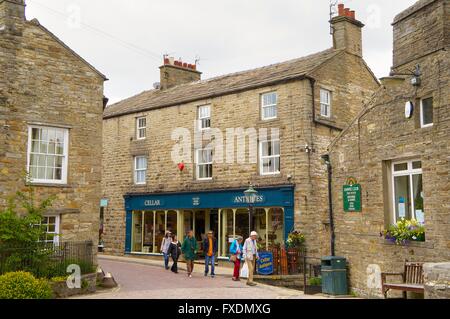Chinese tourists walking past antiques shop in the Main Street. Hawes ...