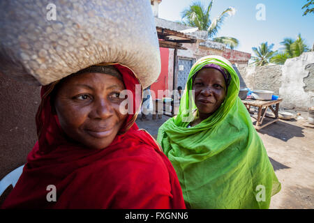 Mozambique, a woman in colored traditional clothes is seated out of the ...