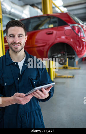Mechanic looking at a tablet computer while holding it Stock Photo - Alamy