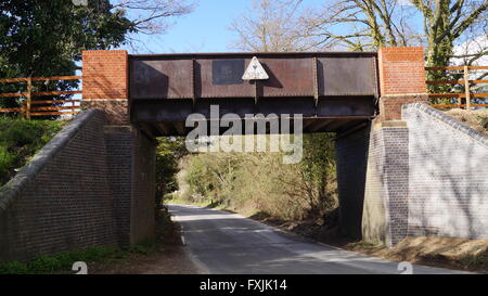 Brick railway bridge with height restriction sign across a road in ...