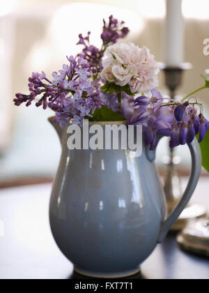 Vase with lilac flowers on table near color wall Stock Photo - Alamy