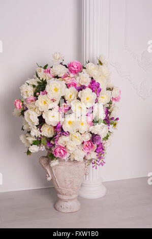 Vase with bouquet of beautiful white lilac on chair against light ...