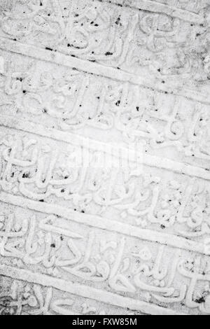 Old stone inscription with Arabic script resting against weathered wall ...