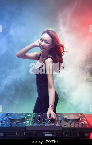 Portrait of young woman as female DJ making music tracks at disco party ...