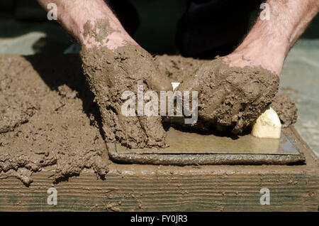 A worker making sustainable mud bricks to construct a greenhouse to ...