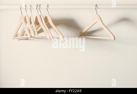 Empty clothes hangers on rack against orange background Stock Photo - Alamy