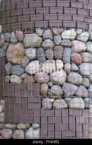 Wall with differently shaped stones in metal mesh Stock Photo - Alamy