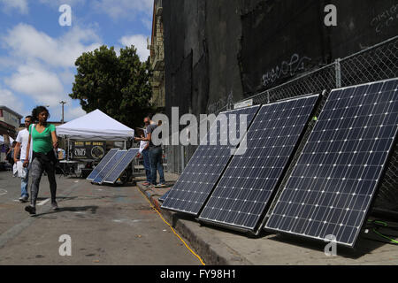 A woman walks past solar panels set up on the street to charge ...