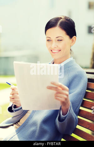 smiling businesswoman reading papers outdoors Stock Photo - Alamy