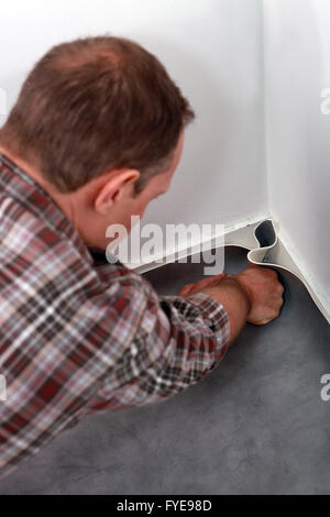 Man pushing lino flooring to fit into a corner Stock Photo - Alamy