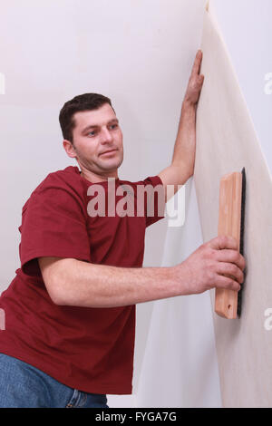 Low shot of a man smoothing wallpaper with a large brush Stock Photo ...