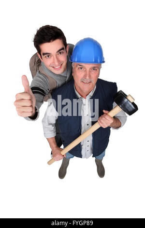 an experienced tradesman posing with his new apprentice Stock Photo - Alamy
