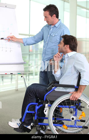An employee pointing at a board and explaining something to a male ...