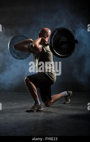 Bald athlete doing exercise with a barbell. Crossfit on the walk ...