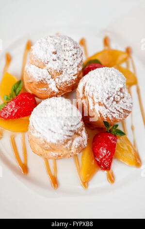 Delicious profiteroles with whipped cream filling on white background ...