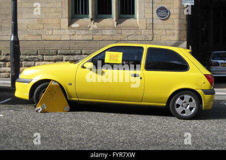 A small yellow car with DVLA Untaxed Vehicle notice in the front window ...