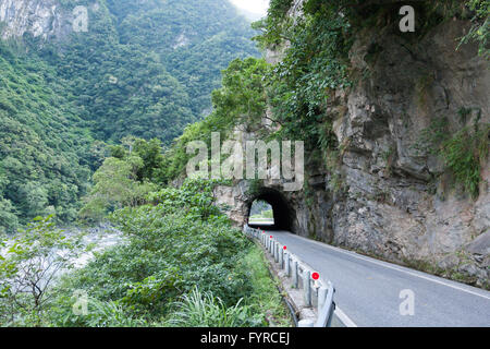 Cliffside road under rock overhang and stream flowing through marble ...