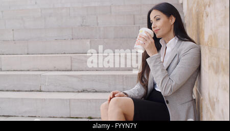 Grinning brunette professional woman sitting on outdoor stairs while ...