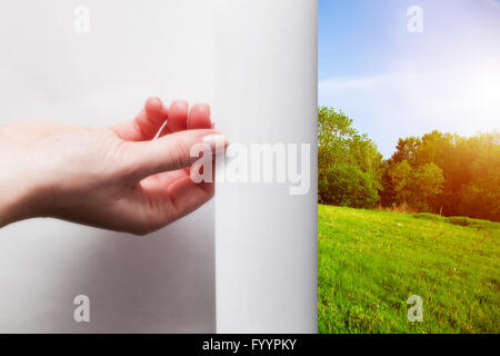Hand pulling edge of a paper to uncover Stock Photo - Alamy