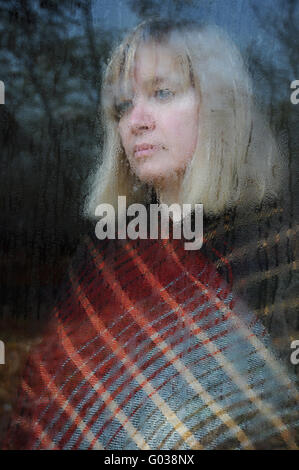 Beautiful girl looking through the window with raindrops on the glass ...