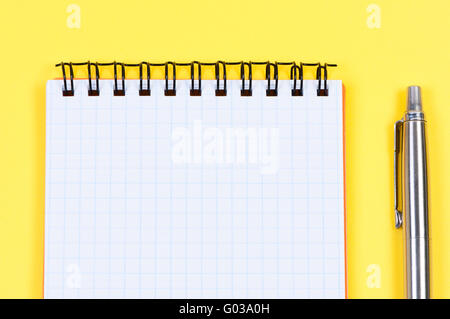 Notebook and ballpoint pen on yellow background Stock Photo - Alamy