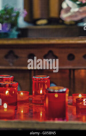 red candles in Catholics church while young girl is holding a match ...