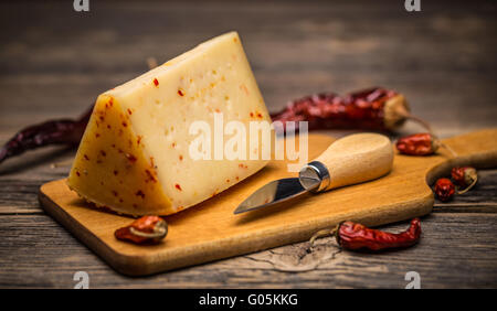Piece of artisan cheese with chilli on wooden cutting board Stock Photo ...
